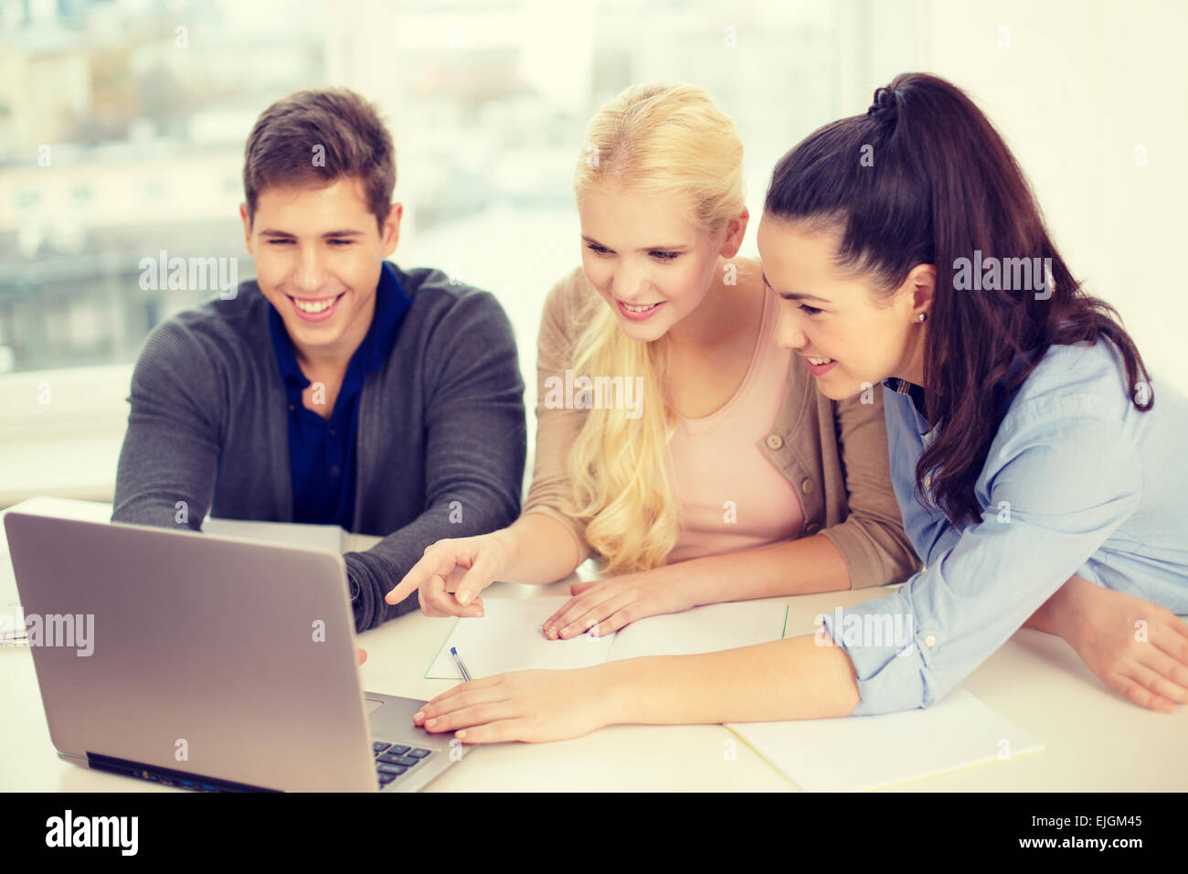 three smiling students with laptop and notebooks Stock Photo - Alamy