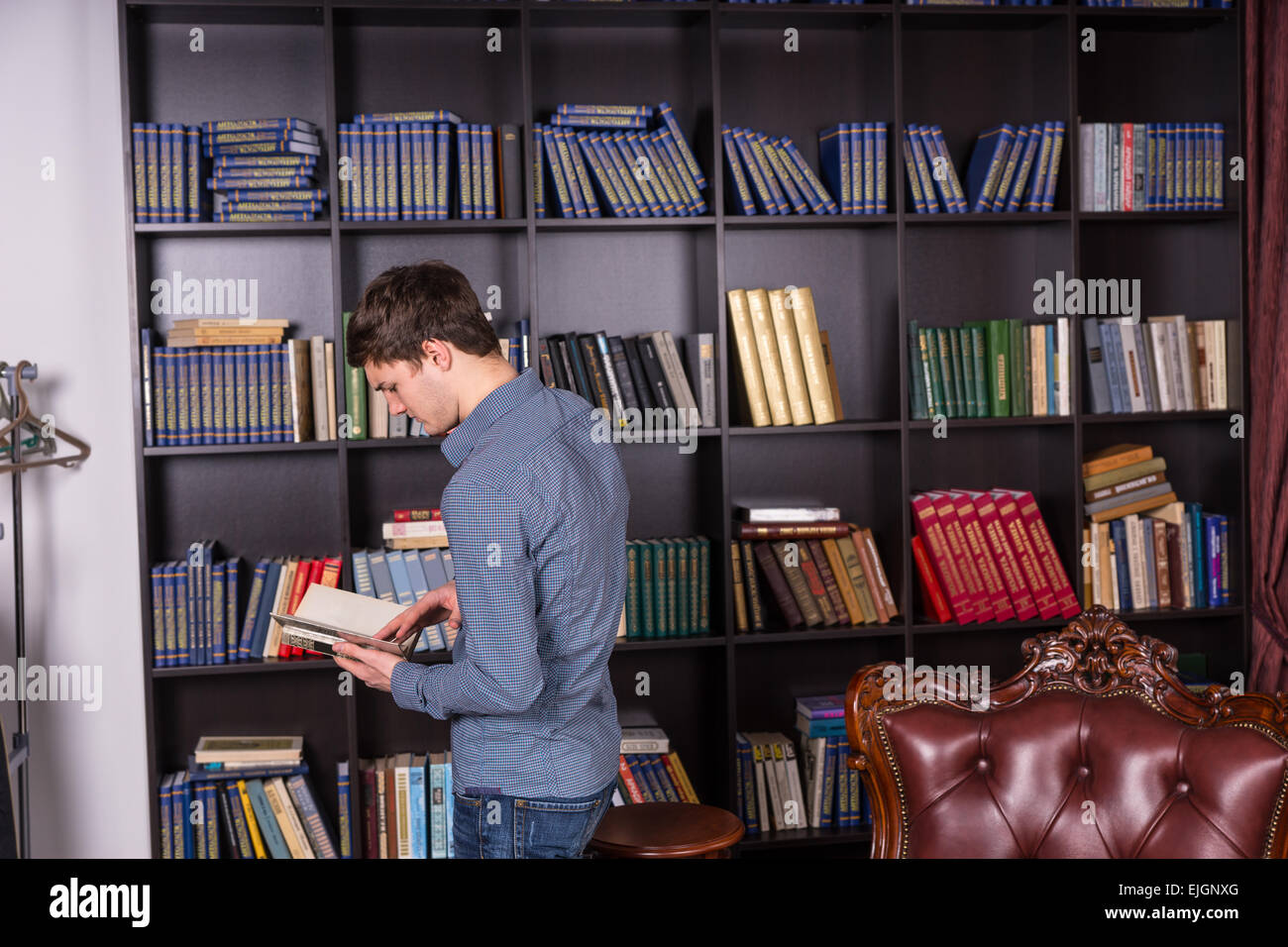 Serious Young Young Man Scanning a Book While Standing In Front of the ...