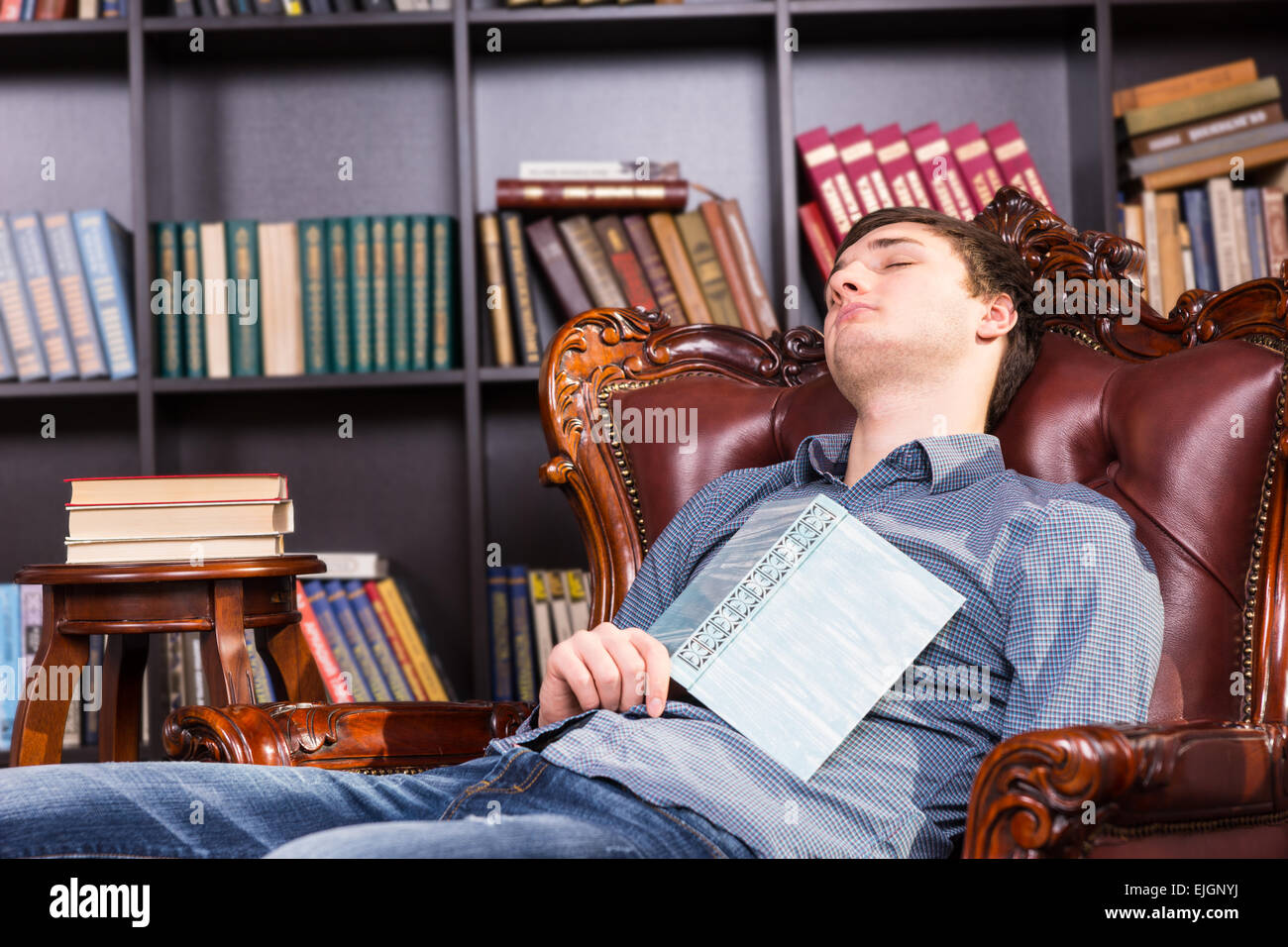 Young man enjoying a nap in the library relaxing in a comfy leather ...