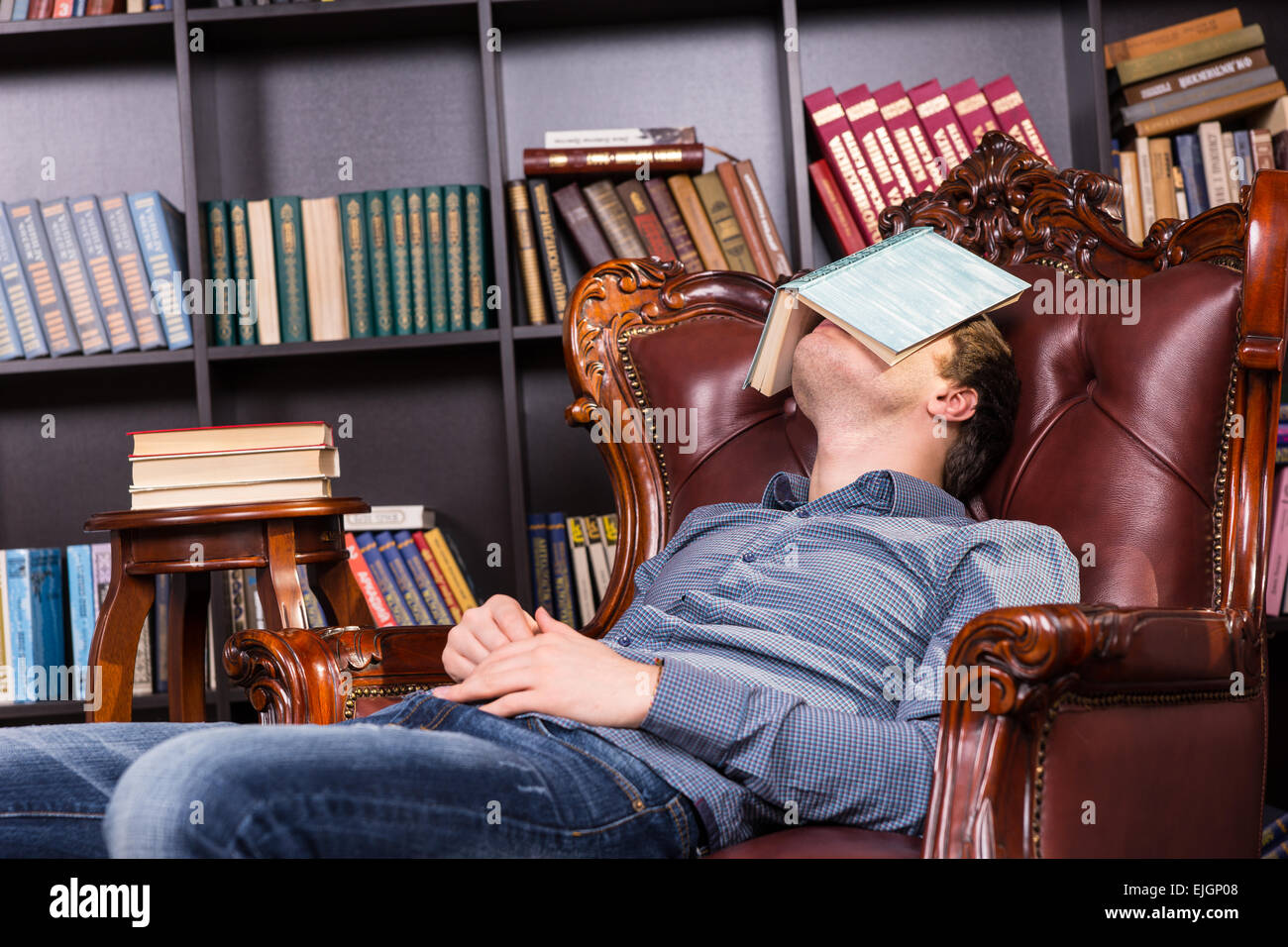 Exhausted young man sleeping in a library relaxing in a comfortable ...