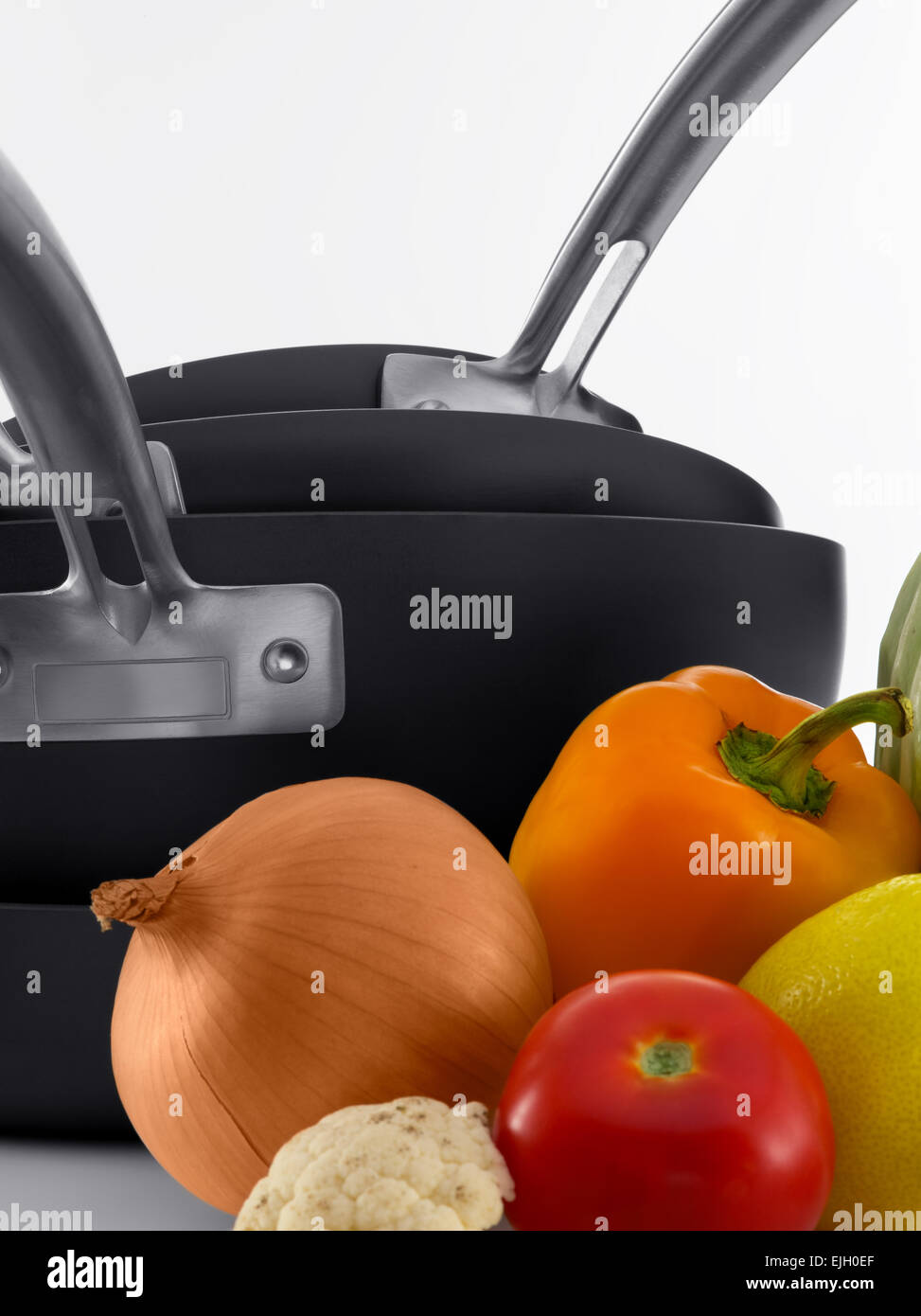 close up view of nice cookware set with some vegetables on grey color ...