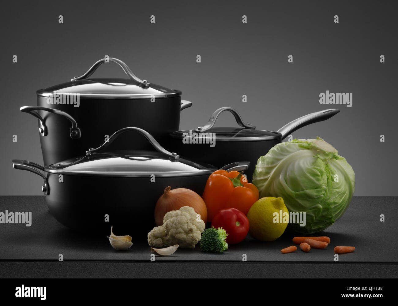 close up view of nice cookware set with some vegetables on grey color ...