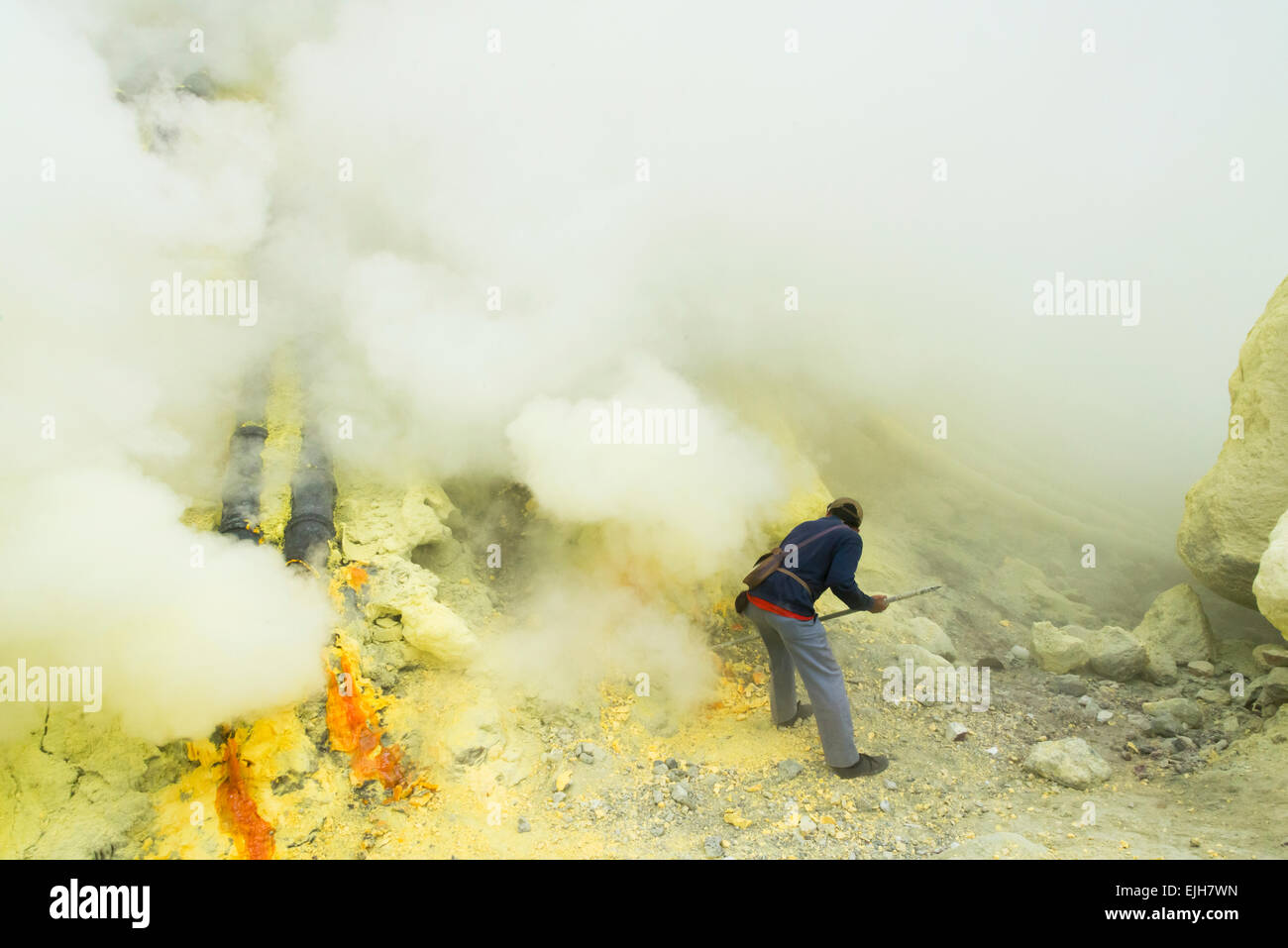 Miner mining sulfur amid sulfur gas, Ijen volcano, East Java, Indonesia ...