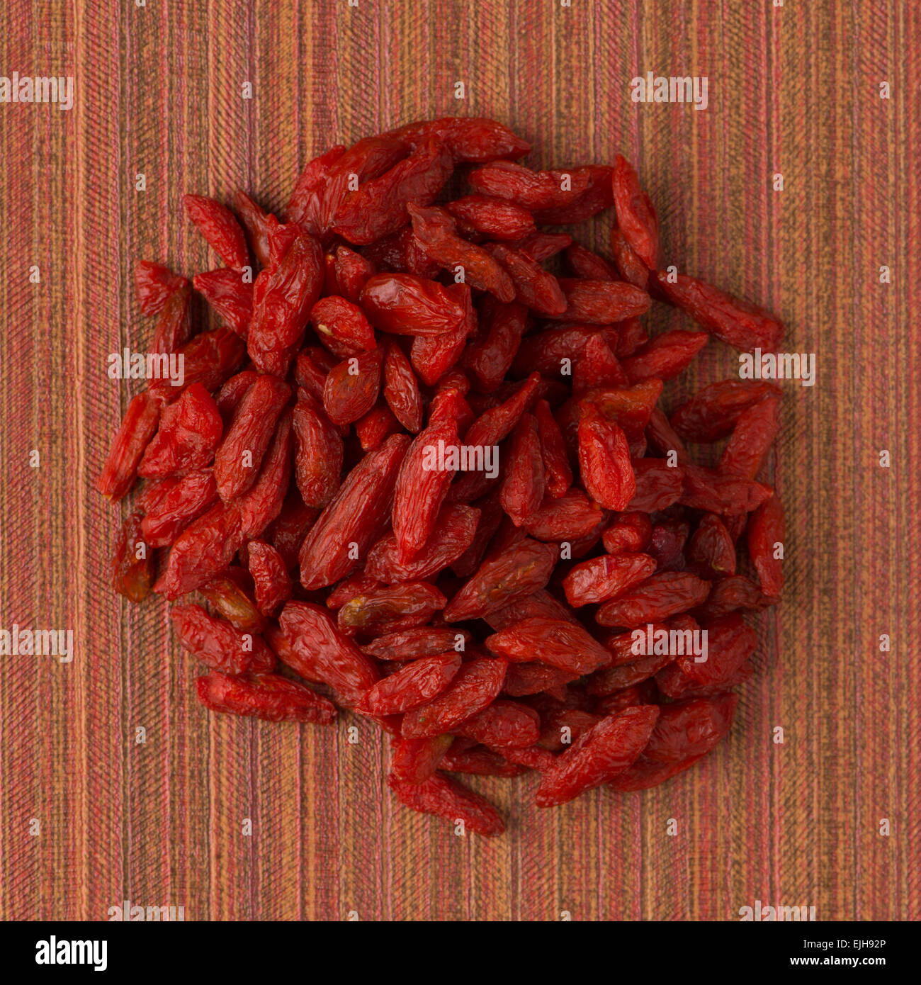 Top view of circle of dry red goji berries against red vinyl background ...