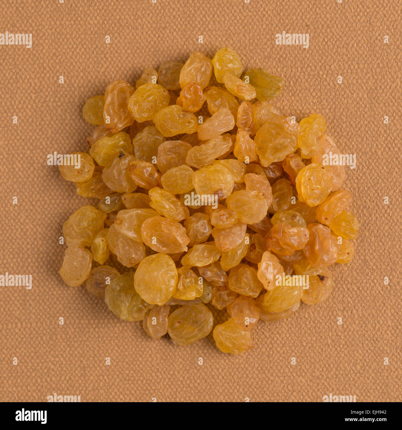 Top view of circle of golden raisins against brown vinyl background ...