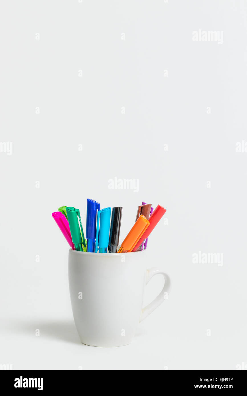 Color markers in a white cup on an isolated background Stock Photo - Alamy