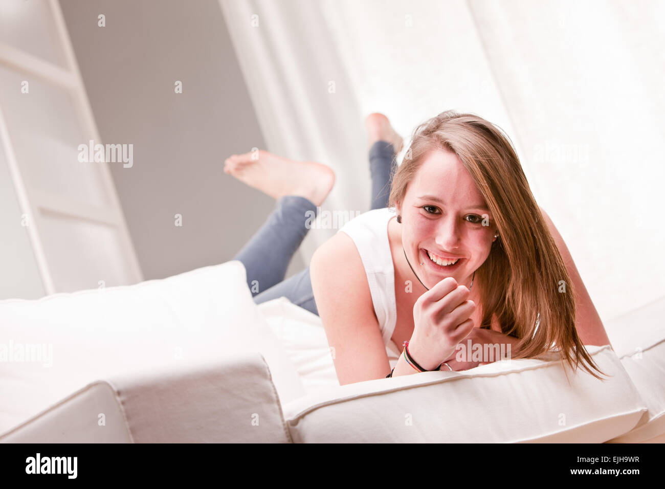 smiling girl in a strange position on a couch staring at you Stock ...