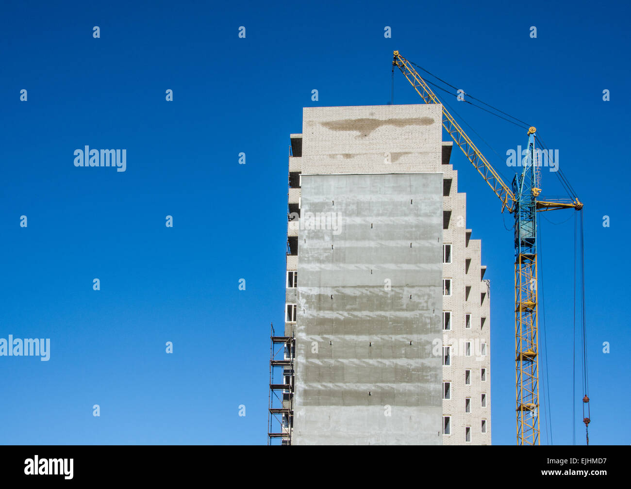 Under construction brick high-rise building with a tower crane on a ...