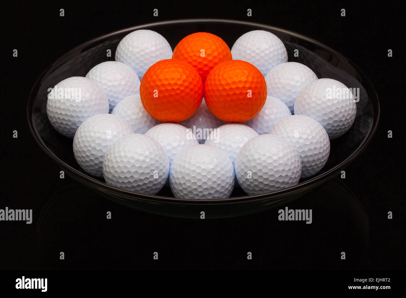 Black ceramic bowl full of white and orange golf balls Stock Photo - Alamy