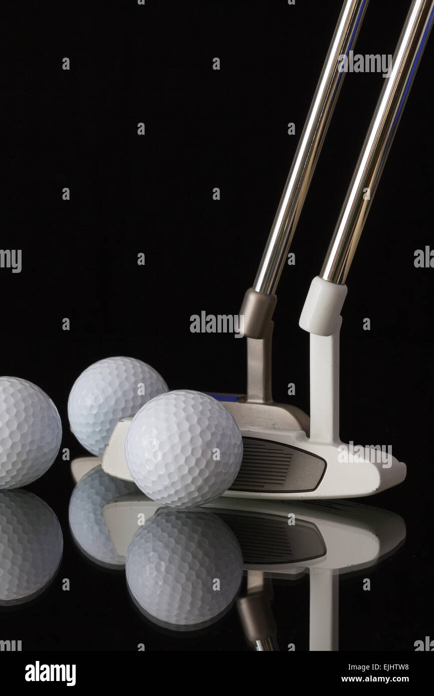 Two different golf putters and three balls on a black glass desk Stock ...