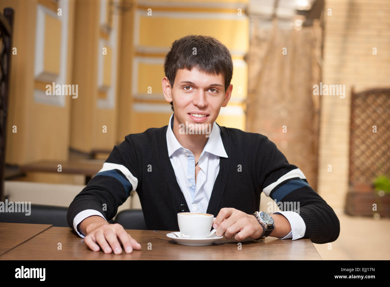 Young man across table with cup of coffee Stock Photo - Alamy