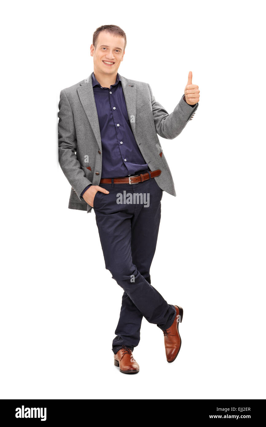 Full length portrait of a handsome young man leaning against a wall and ...