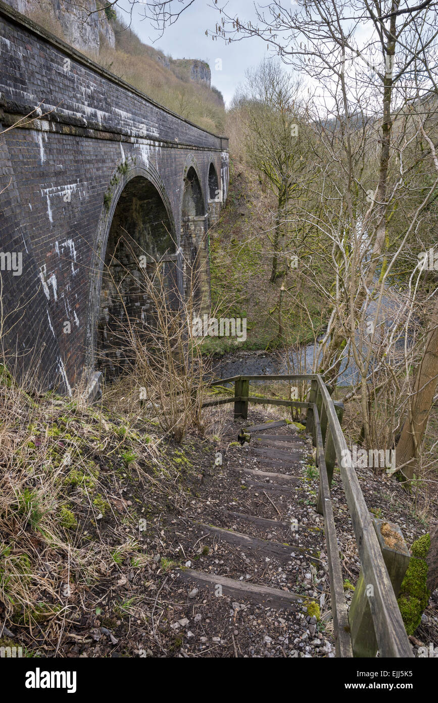 Steps down to the river Wye in Chee Dale with a brick railway bridge on ...