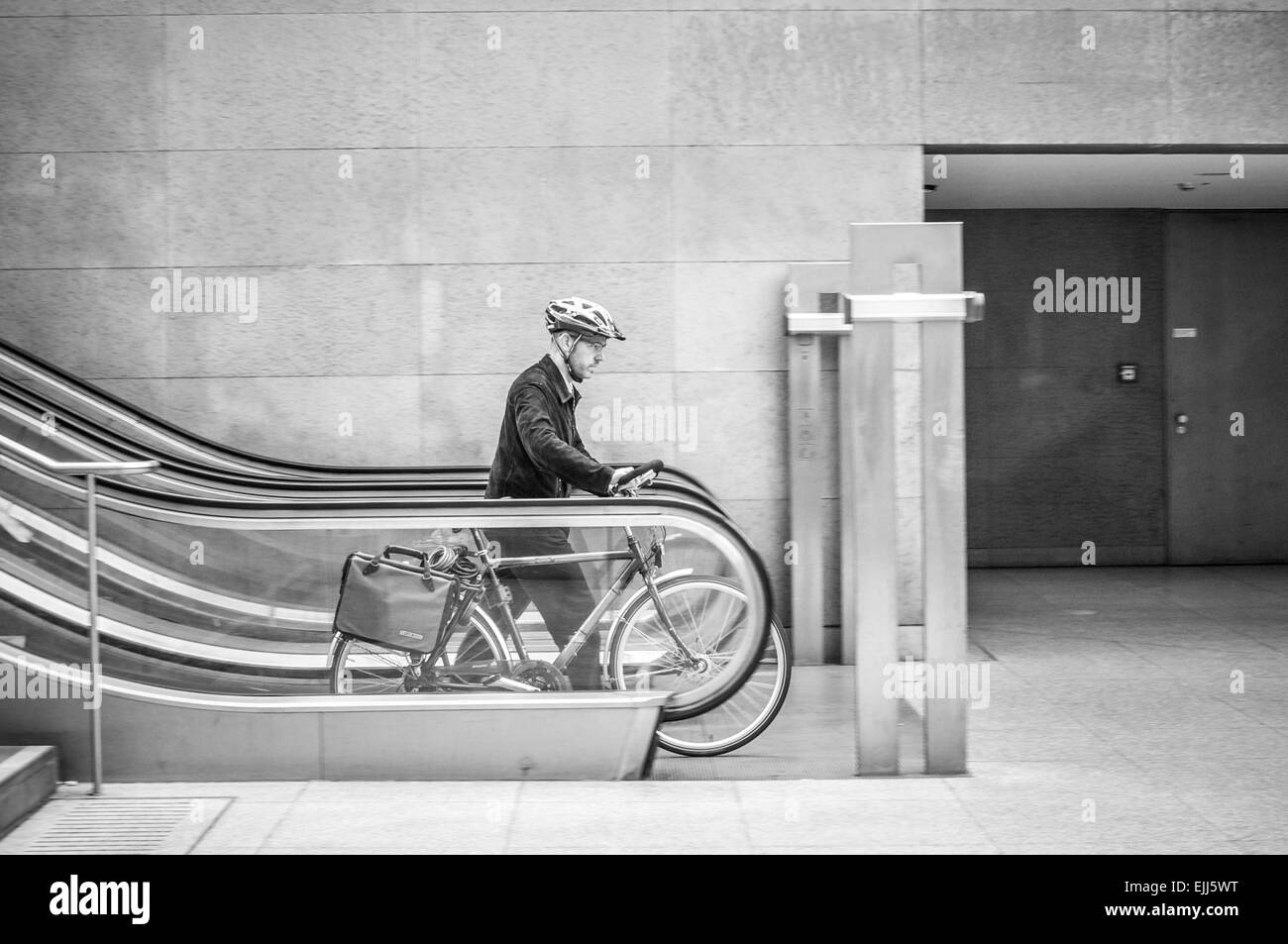 A man taking his bicycle down an escalator into the train station below ...