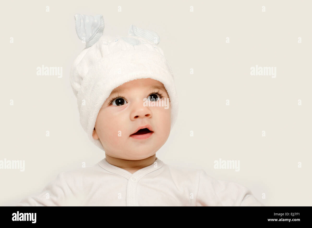 Innocent baby wearing a white hat looking adorable. Kid dressed for ...