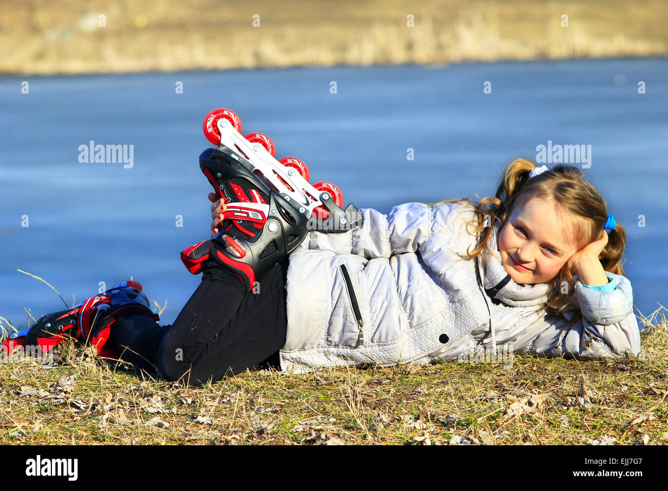 young girl in roller skates lays on the ground and smiles Stock Photo ...