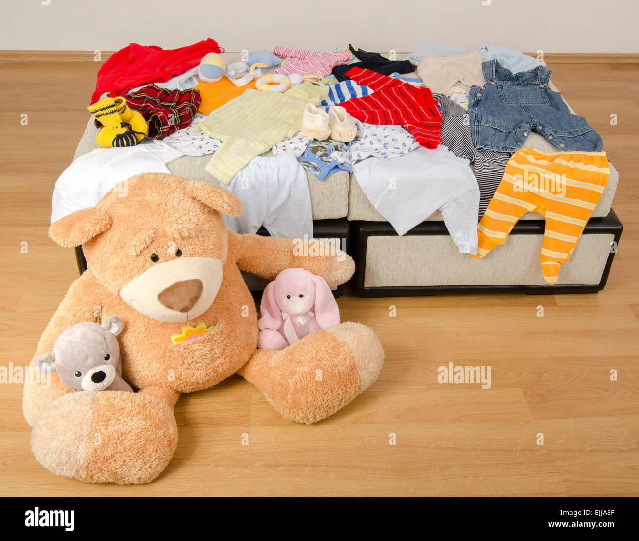 Bear toy on a bed with different colorful new born clothes.Colorful ...
