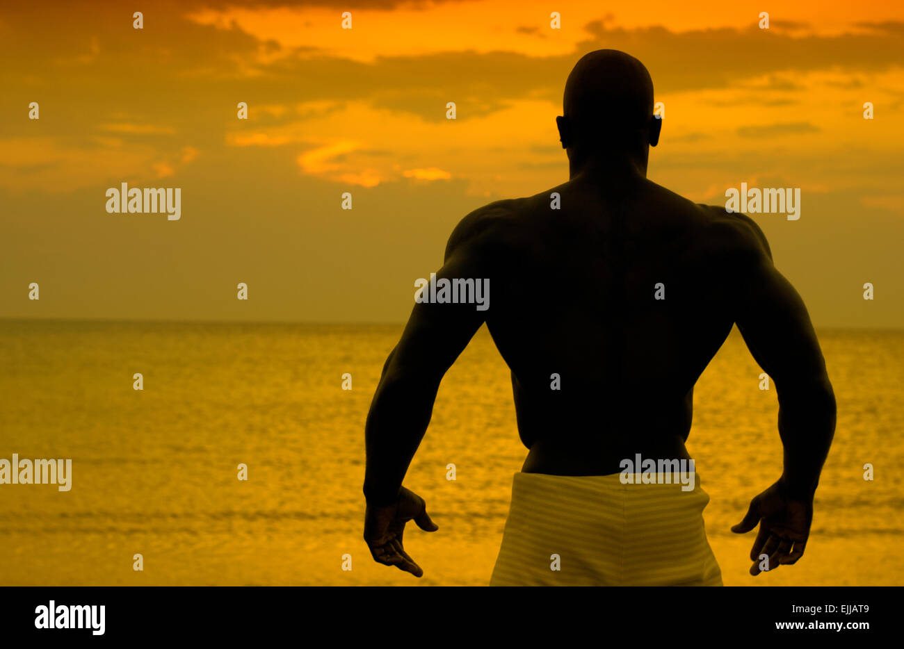 Silhouette of bodybuilder posing at the sunrise on the beach, training ...