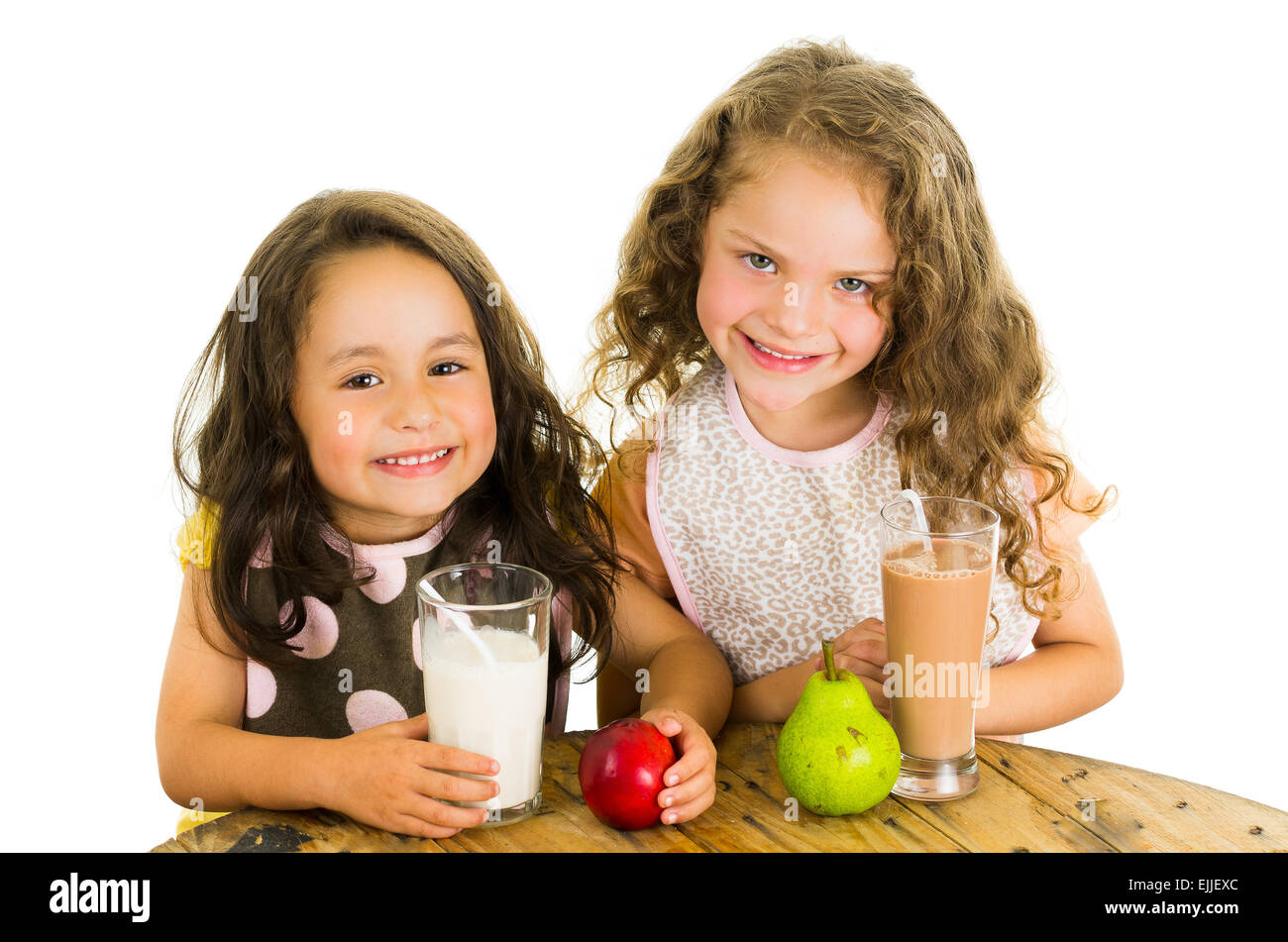 Cute little preschooler girls drinking milk and eating fruits Stock ...