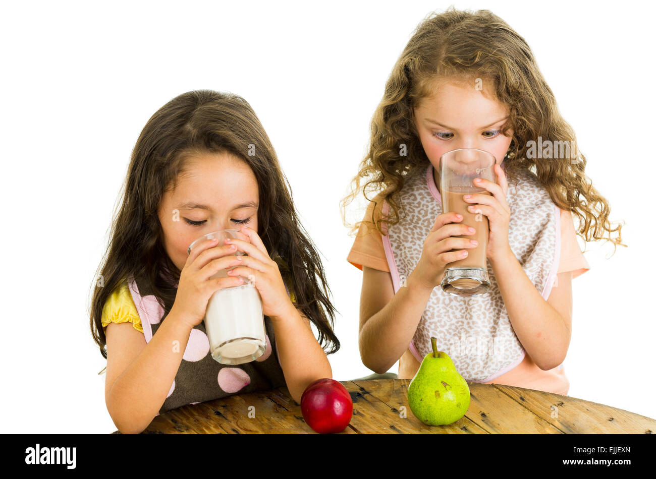Cute little preschooler girls drinking milk and eating fruits Stock ...