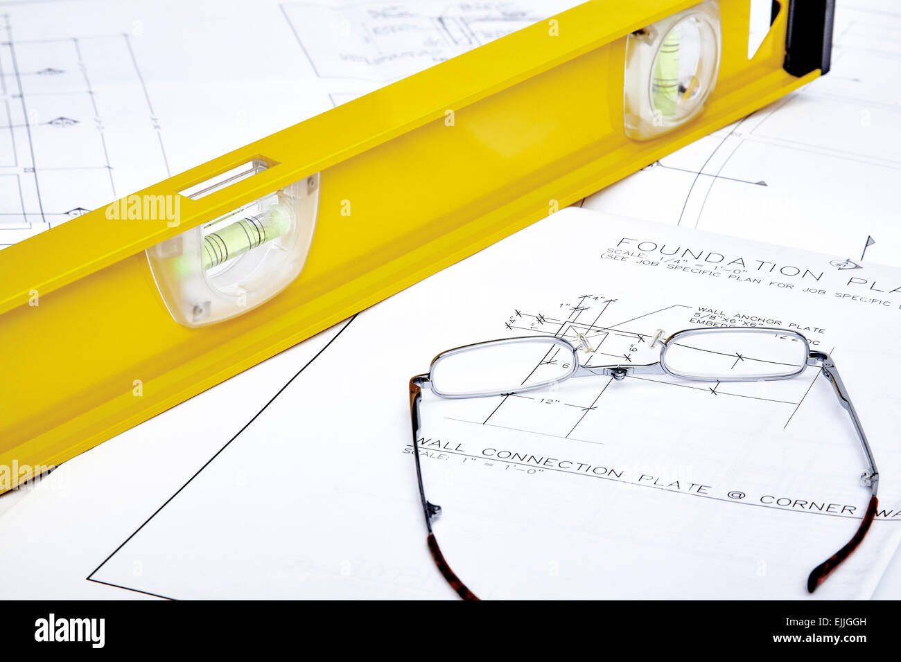 A set of blueprints with reading glasses and a yellow level Stock Photo ...