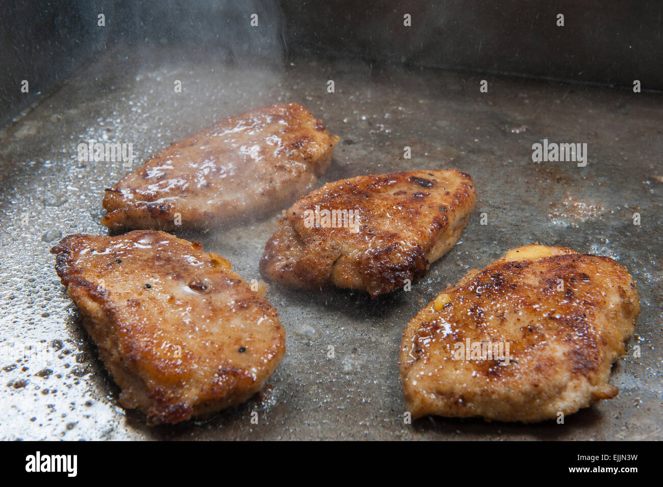 Closeup of chicken escalope panne cooking on grill hot plate at a hotel ...