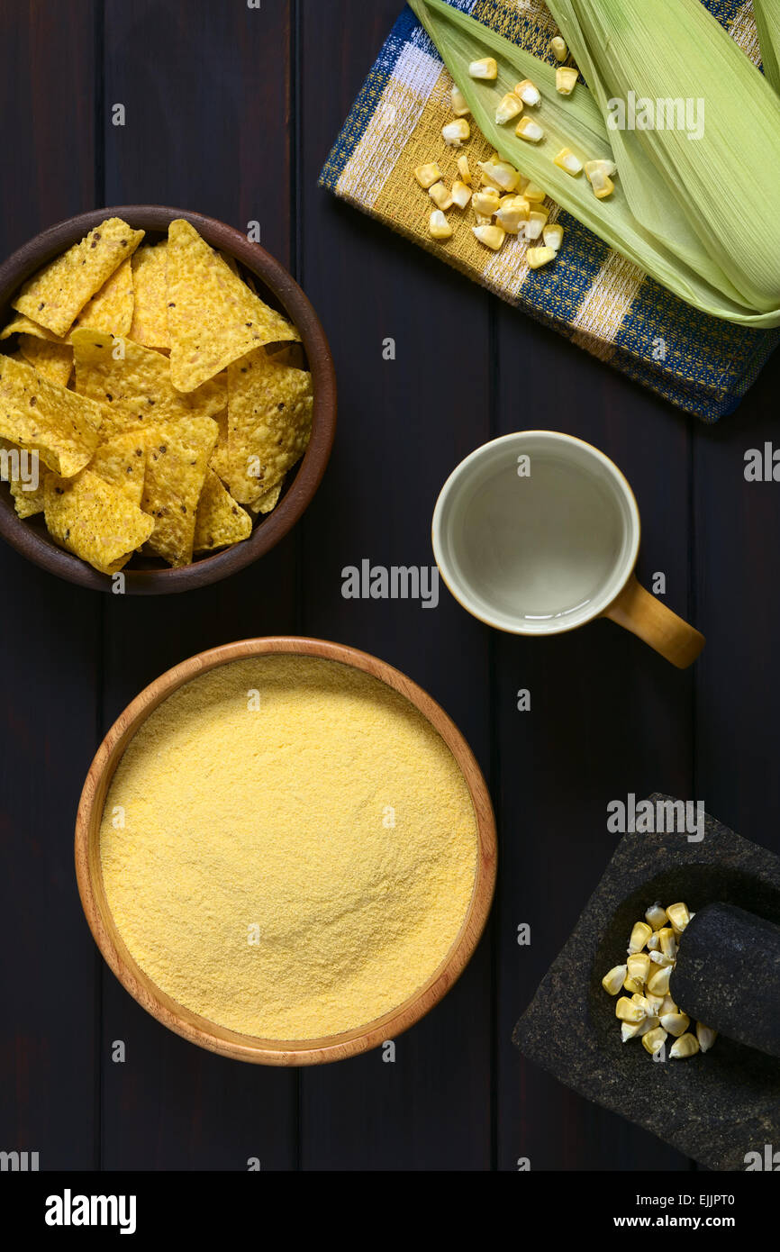 Overhead shot of cornmeal in wooden bowl with cob of corn, corn kernels ...
