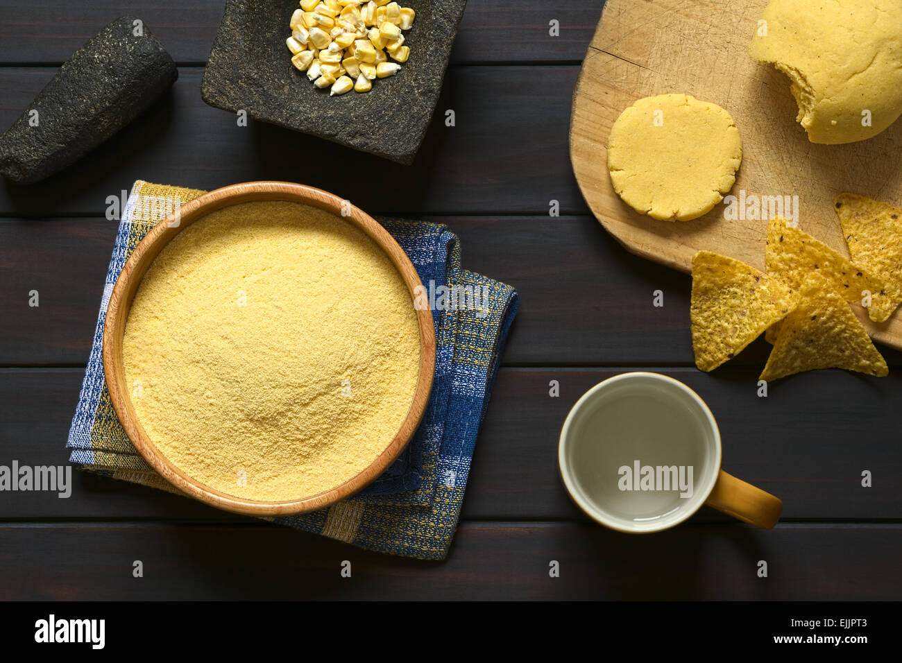 Overhead shot of cornmeal in wooden bowl with corn kernels in mortar ...