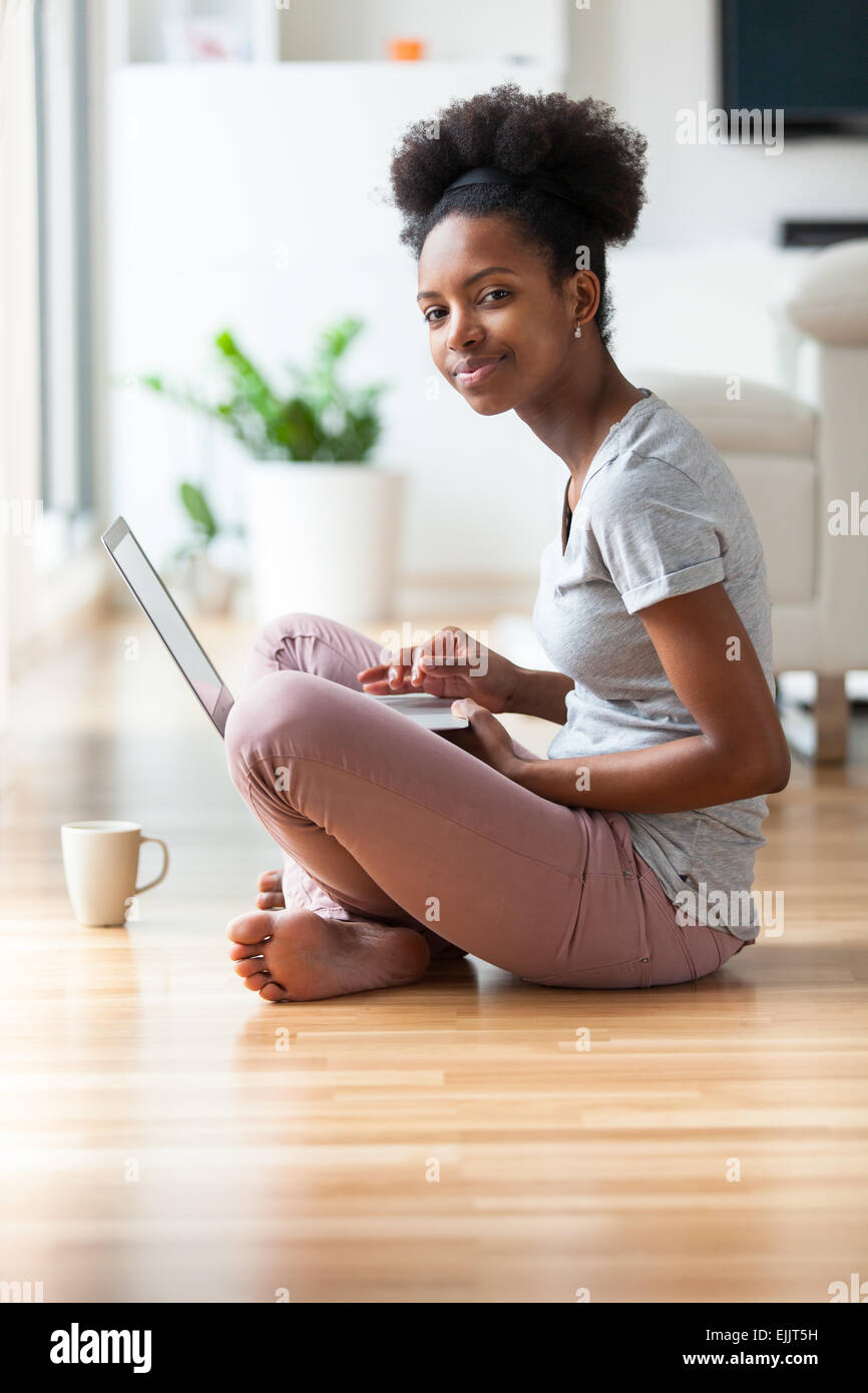 African American woman using a laptop in her living room - Black people ...
