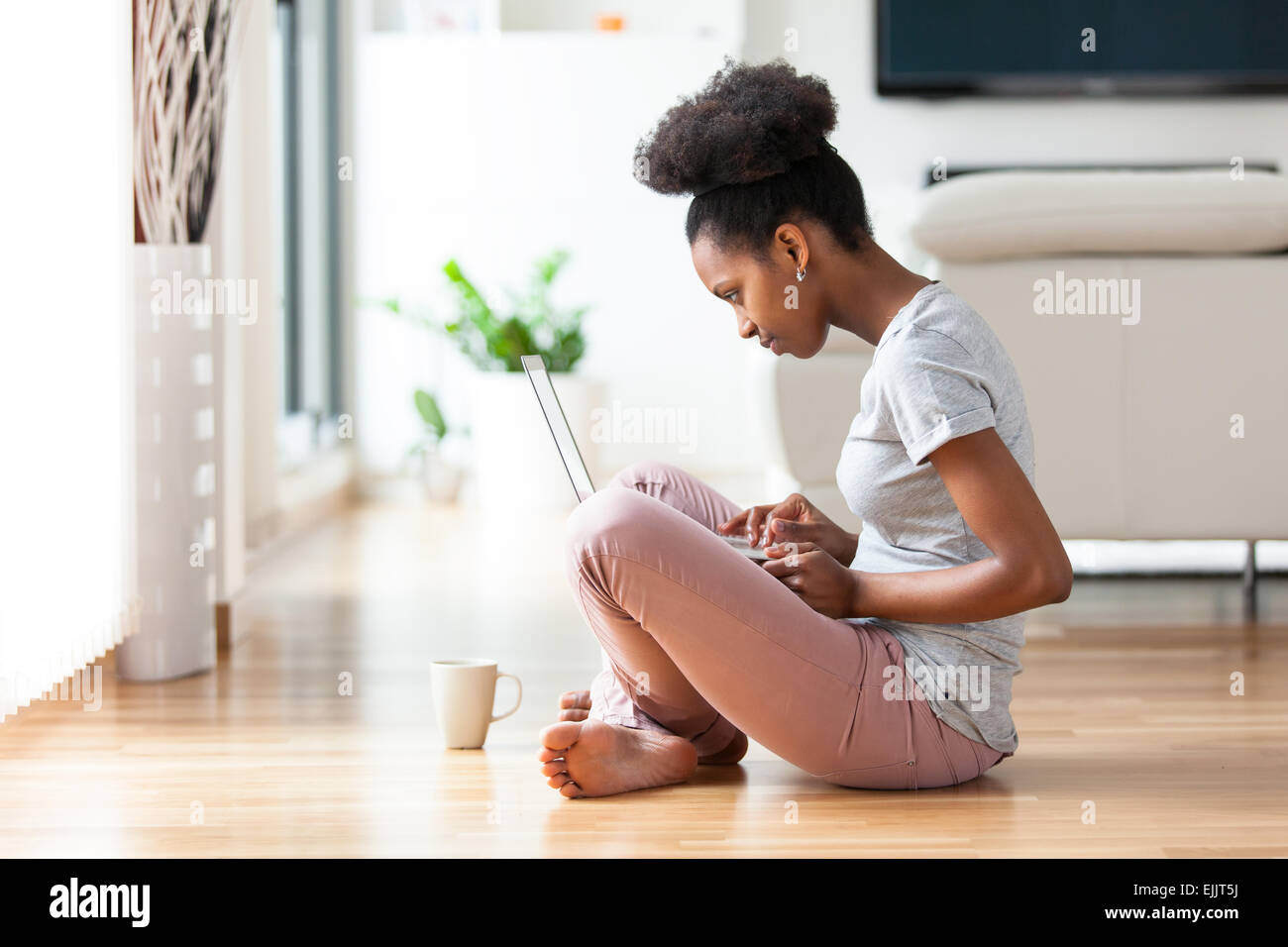 African American woman using a laptop in her living room - Black people ...