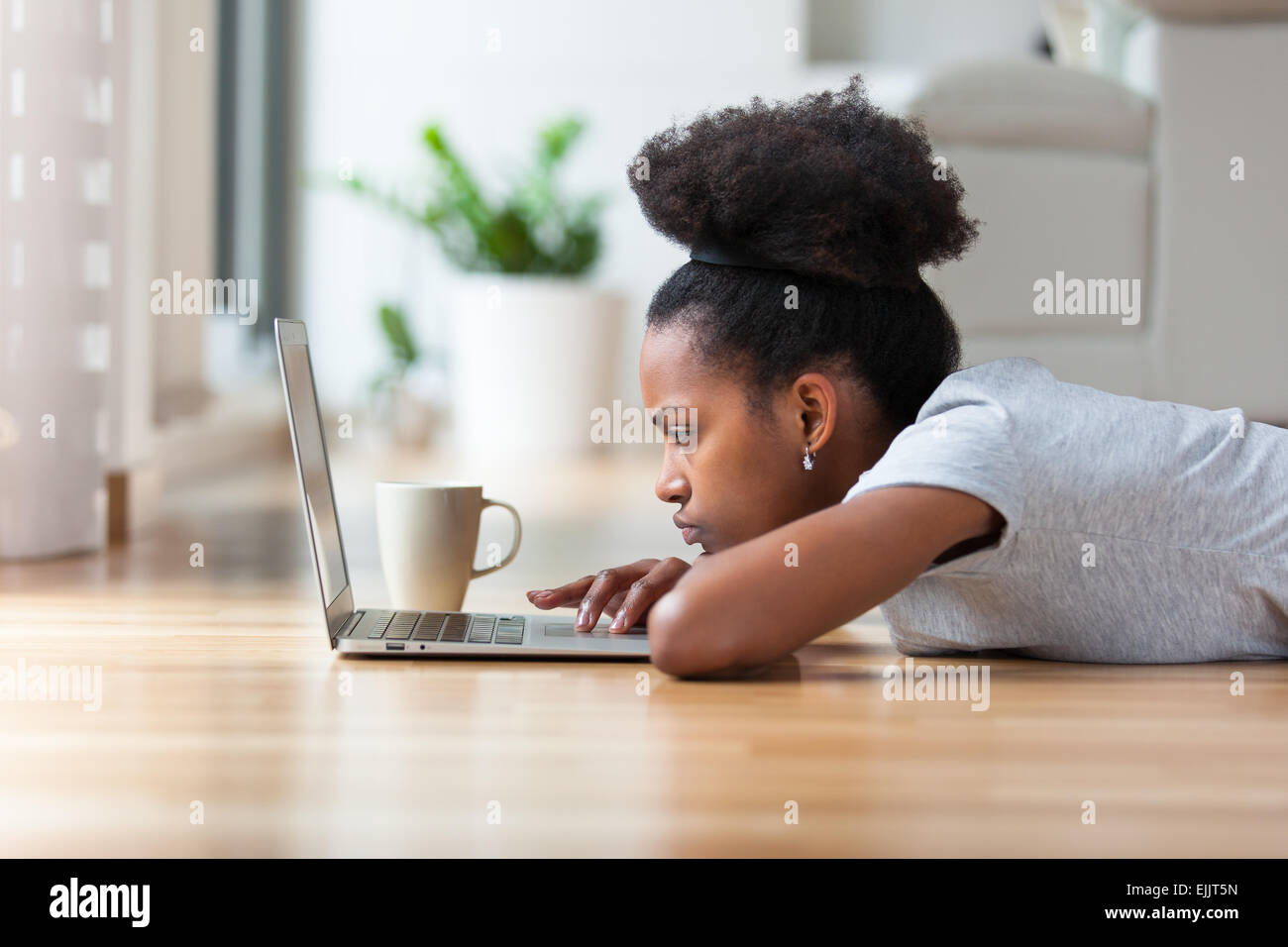 African American woman using a laptop in her living room - Black people ...