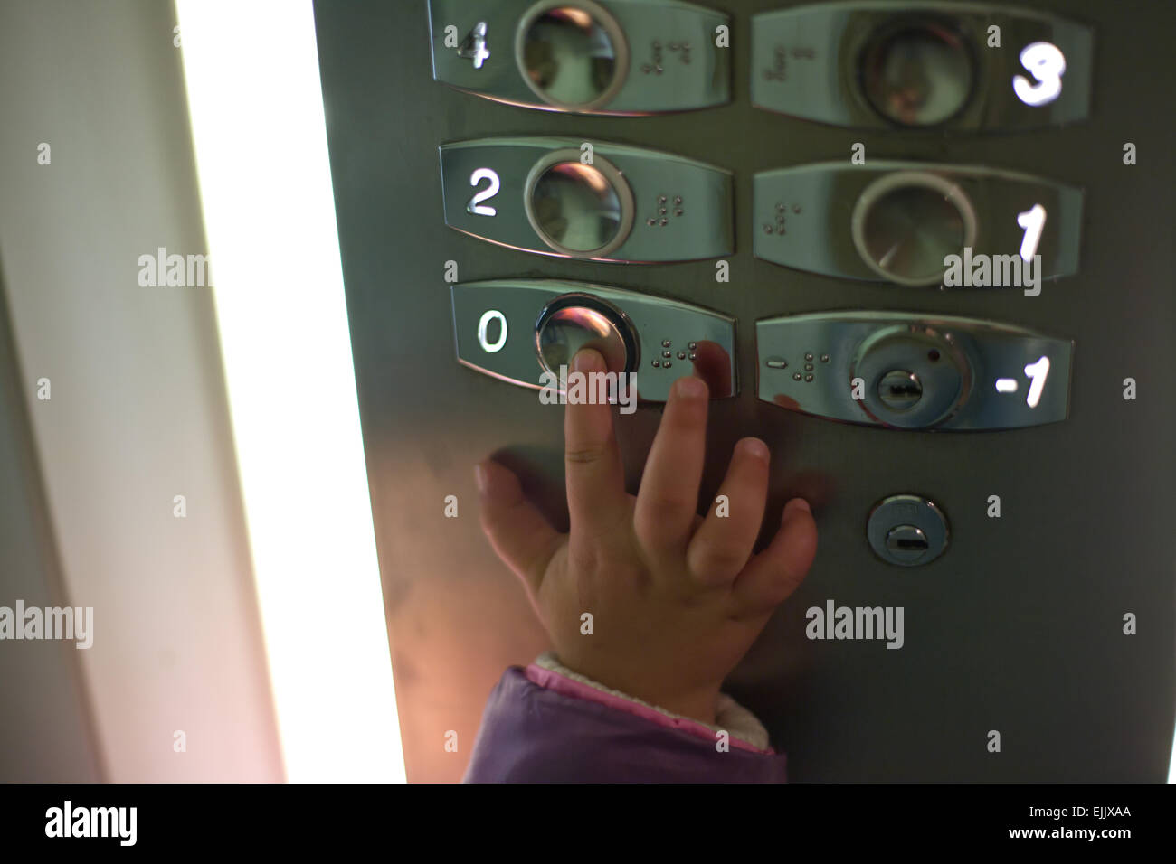 Hand of a toddler in elevator or lift pressing the button to get the ...