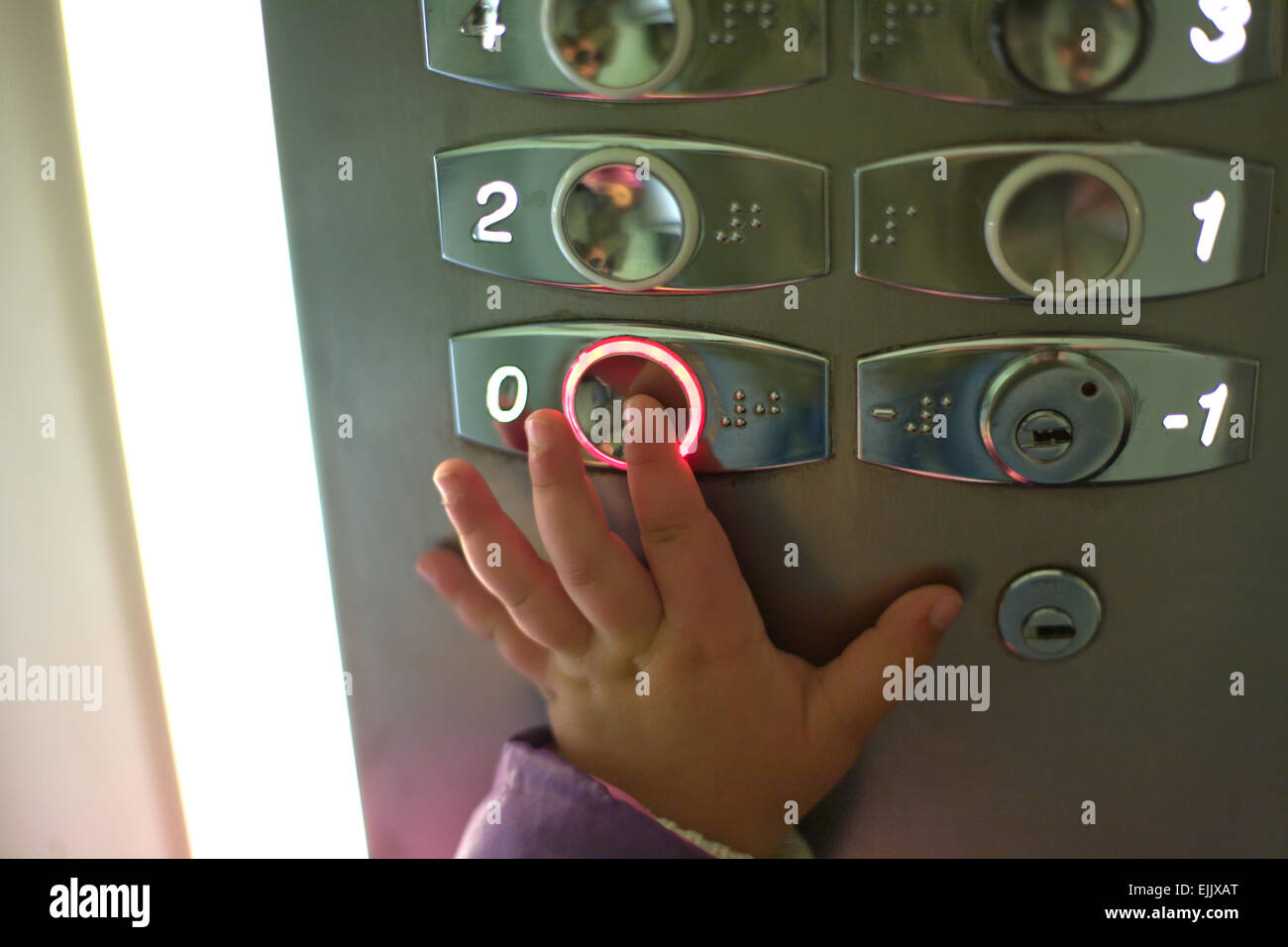 Hand of a toddler in elevator or lift pressing the button to get the ...