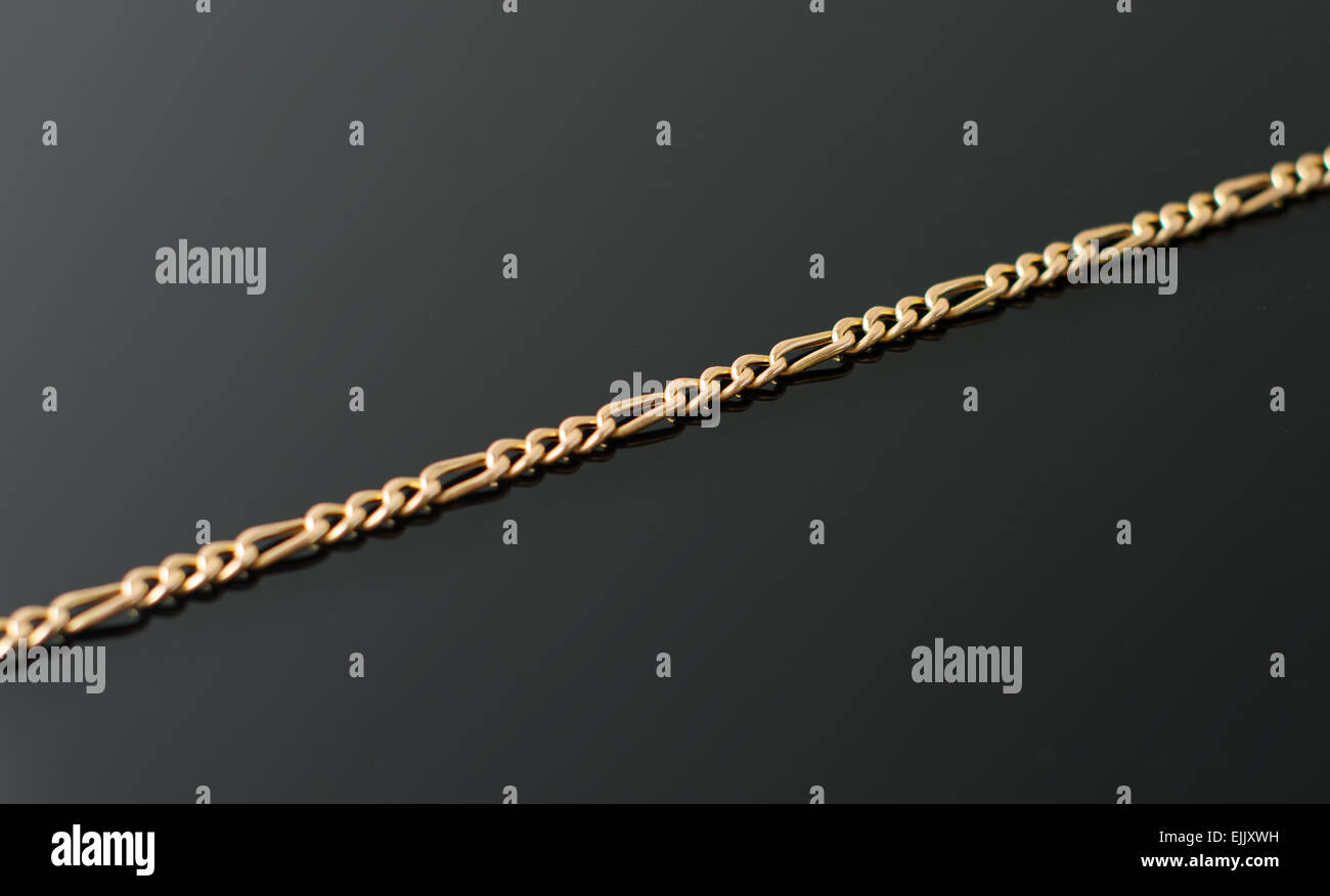 Gold chain lying on black table Stock Photo - Alamy
