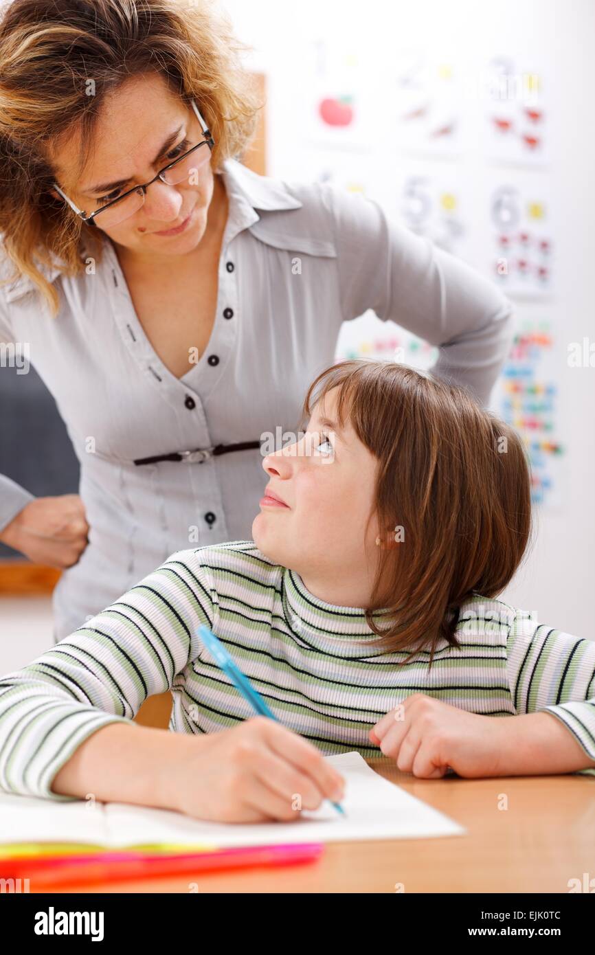 Severe teacher standing behind and looking at schoolgirl Stock Photo ...