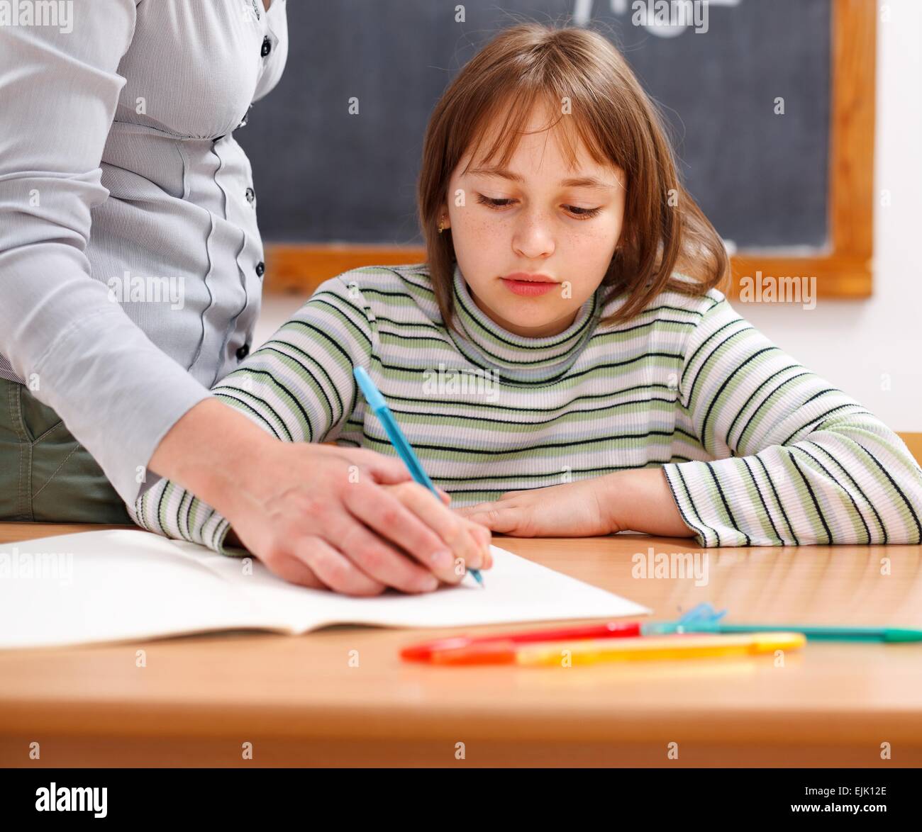 Teacher showing writing by holding hand of elementary school student ...