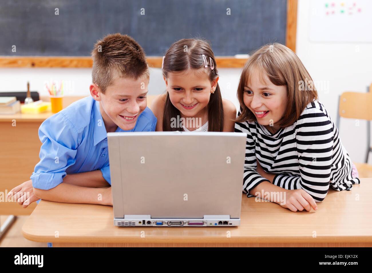 Happy children looking at laptop computer, surfing interesting content ...