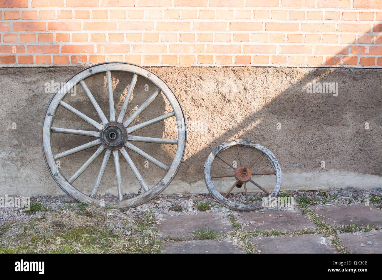 Rustic old wood wheels leaning against brick wall, sunshine and shadow ...