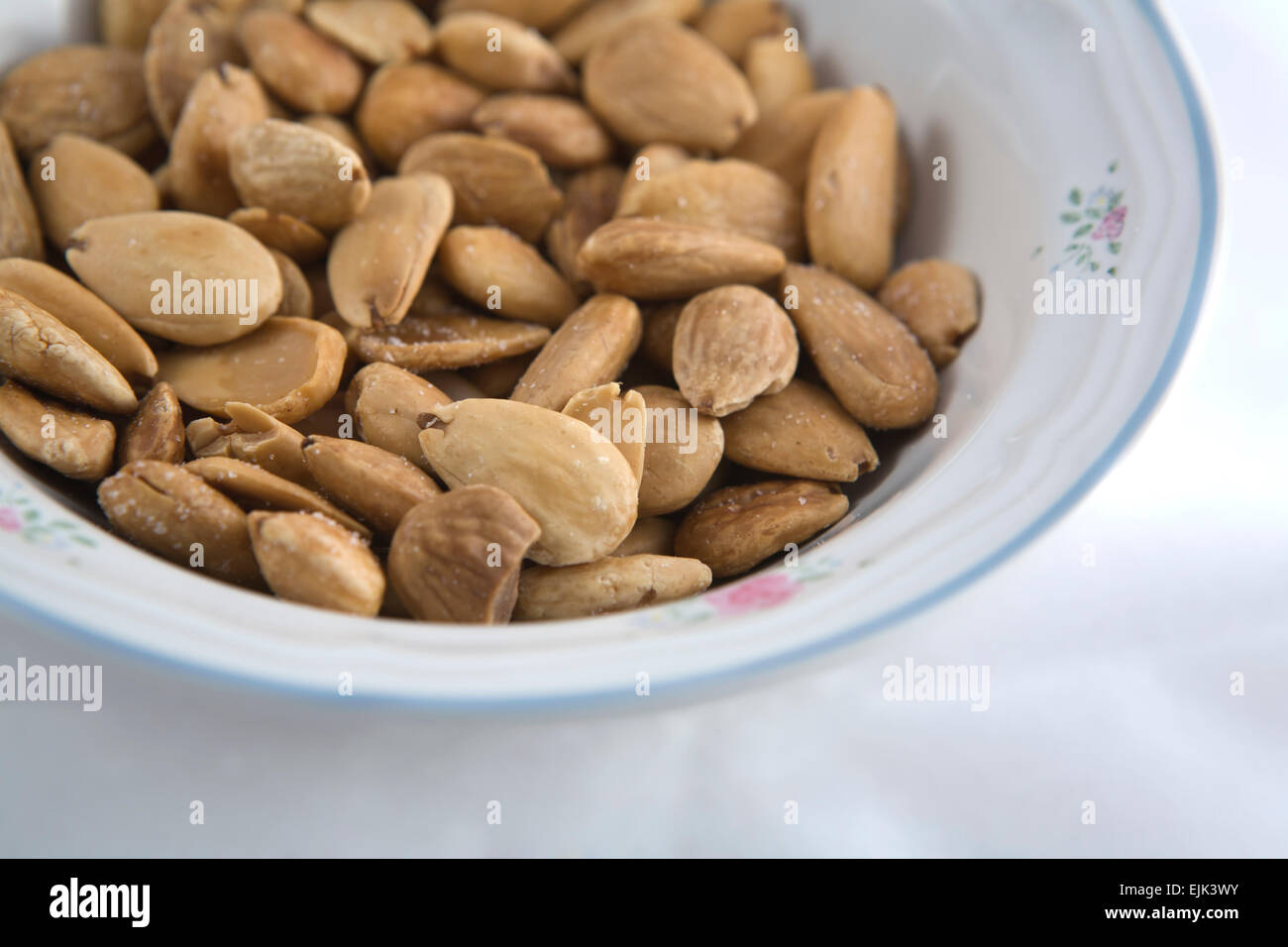 Fried almonds slightly salted isolated over white background in a bowl ...