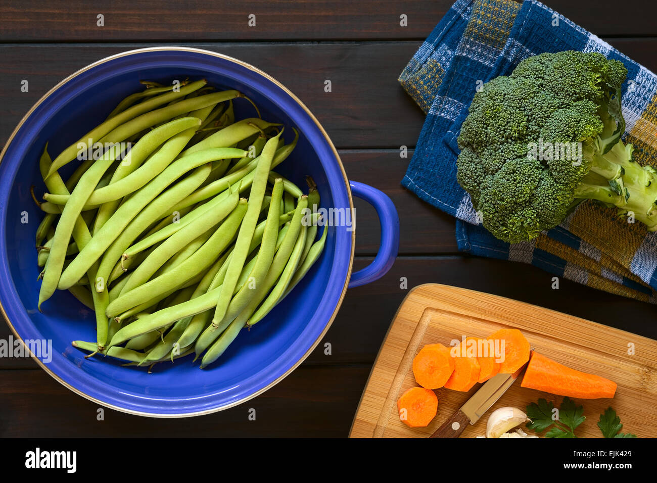 Overhead shot of green beans in blue metal strainer with broccoli, and ...