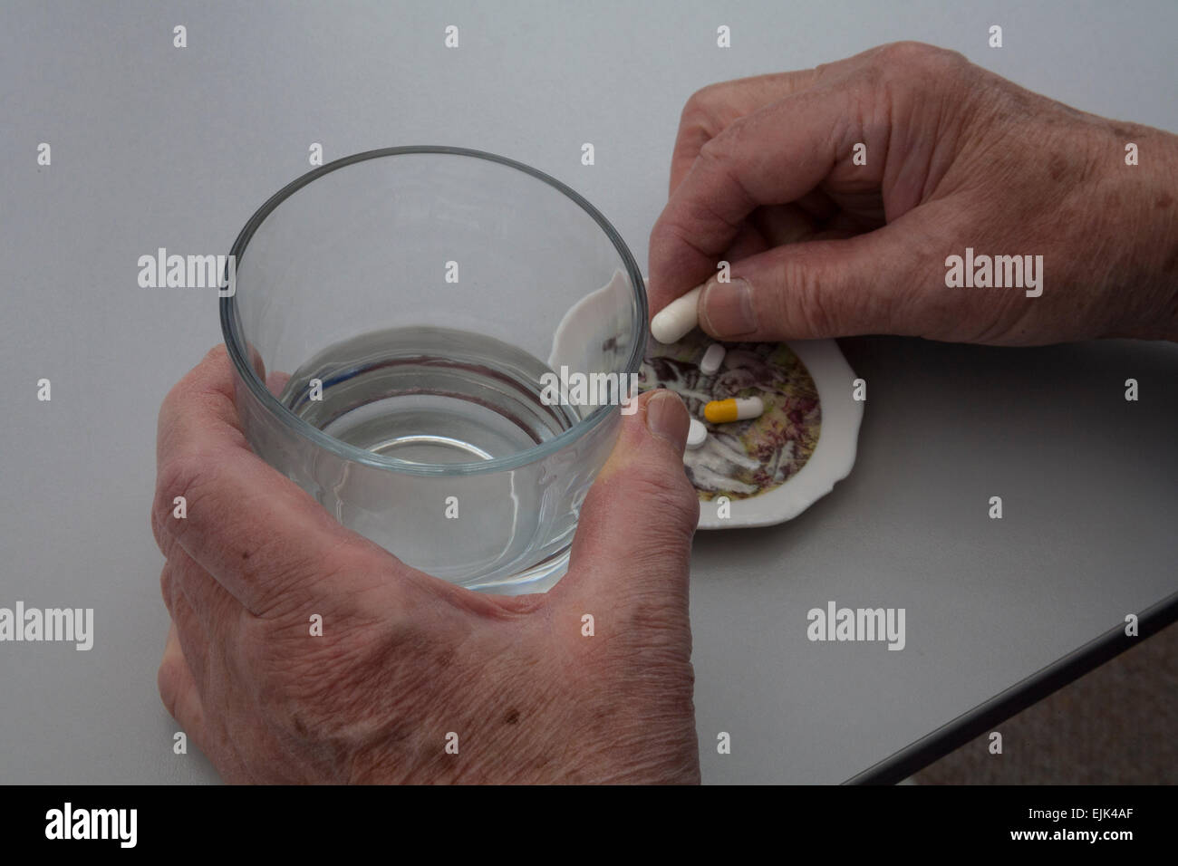 Elderly woman taking prescription medication with glass of water for ...