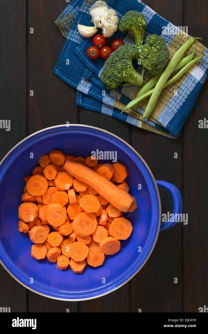 Overhead shot of fresh raw sliced carrot in blue metal strainer with ...
