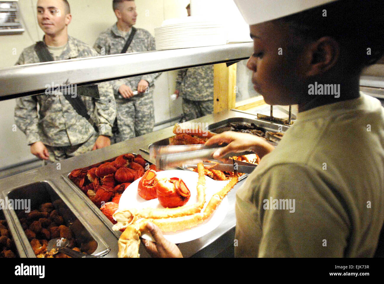 Army Spc. Kiana Mealey serves up lobster tails and crab legs at an Army ...
