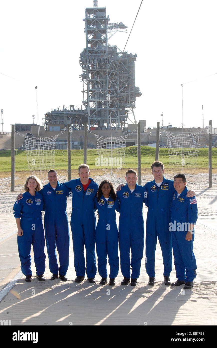 Image right: Crewmembers link arms with space shuttle Discovery behind ...