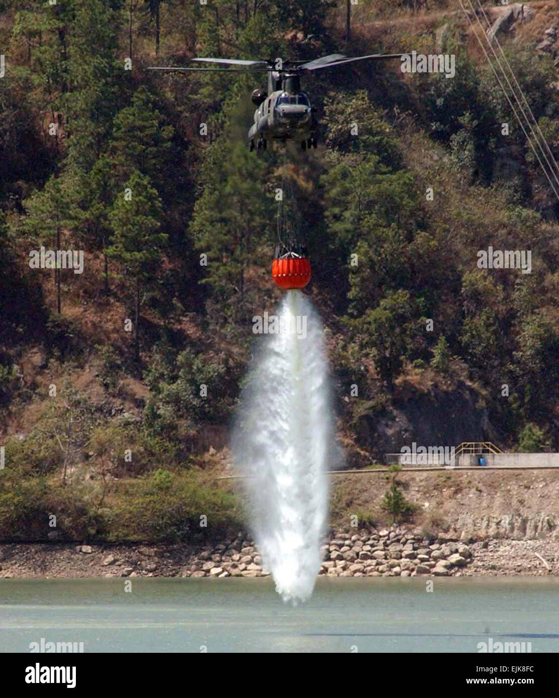 A U.S. Army CH-47 Chinook helicopter drops water from a Bambi Bucket ...