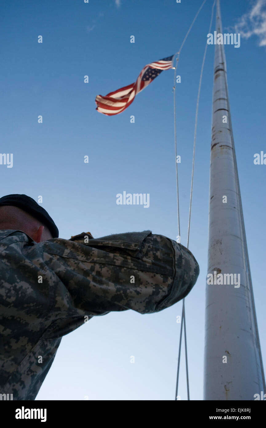 A Soldier renders honors to the American flag as it is lowered to half ...