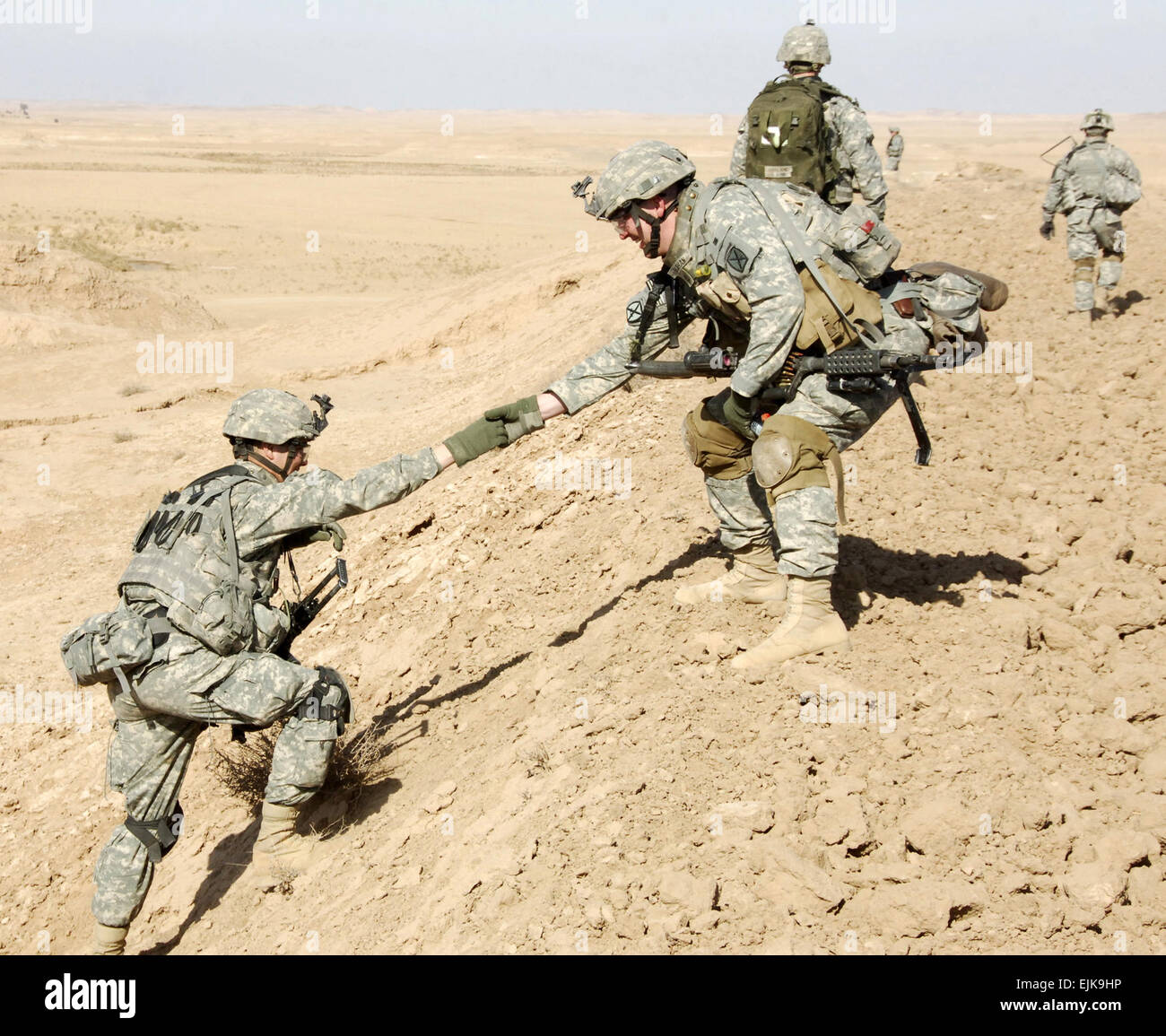 U.S. Army Pfc. Ryan Mahan helps Spc. Stephen McLain up a hill in ...