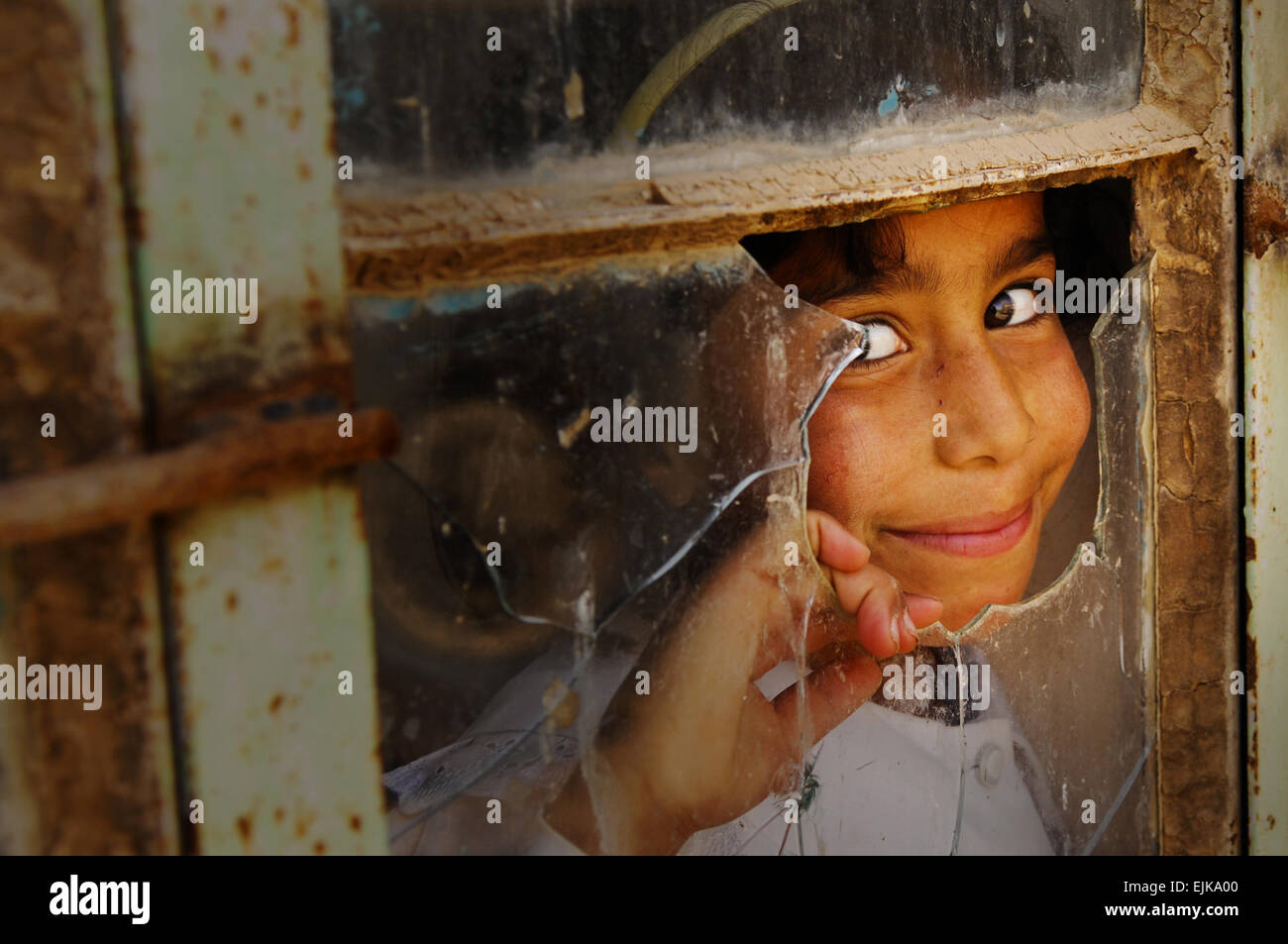 An Iraqi girl peeks out of a broken classroom window to watch as U.S ...