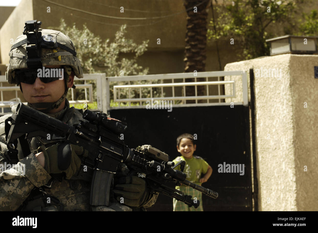 An Iraqi boy smiles behind U.S. Army Sgt. 1st Class Brian Snyder ...