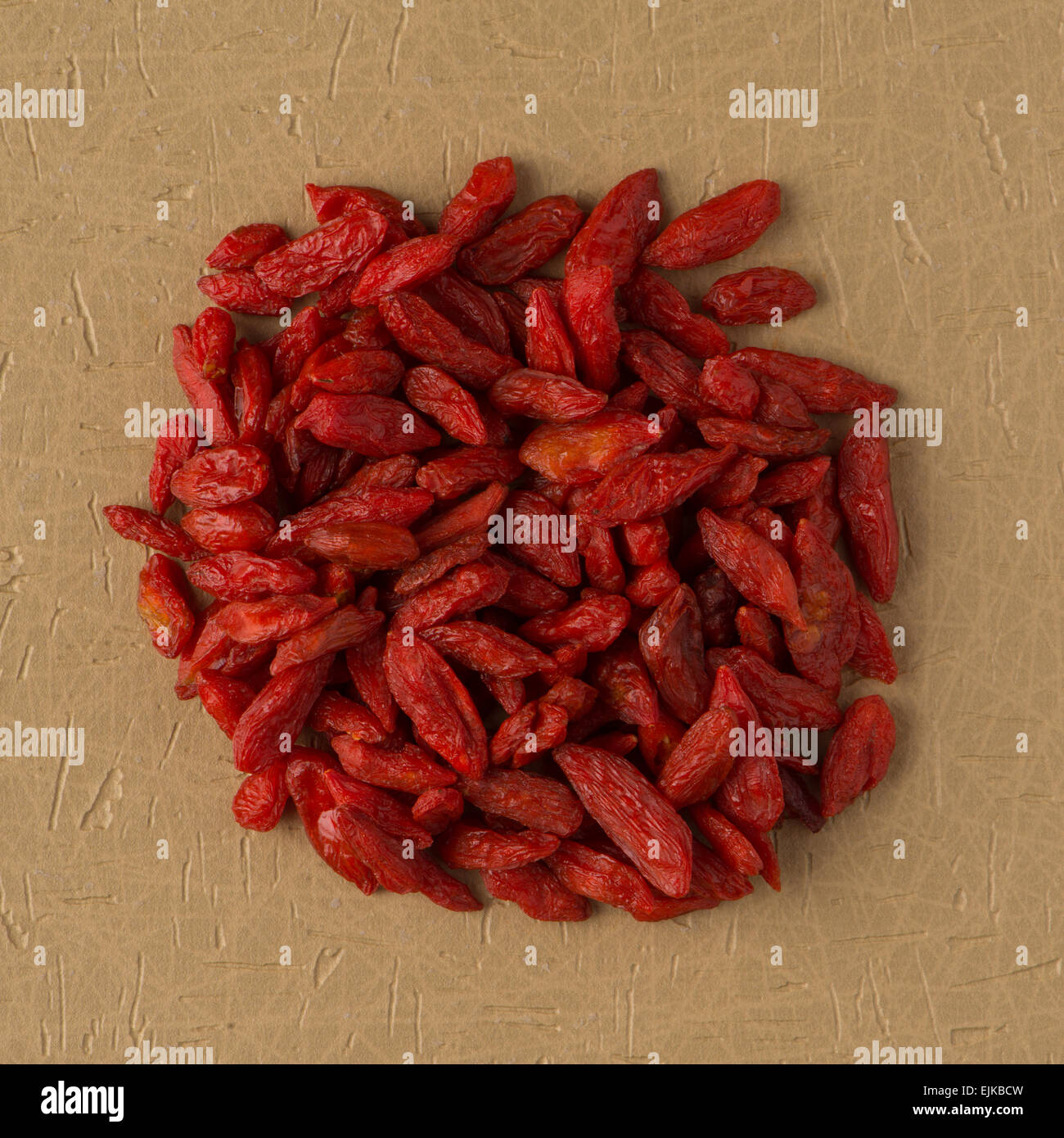 Top view of circle of dry red goji berries against brown vinyl ...
